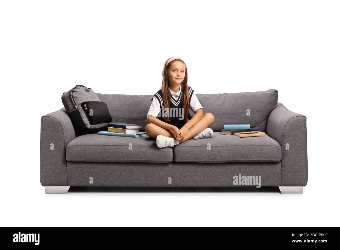 Schoolgirl in a uniform sitting on a sofa with books and a backpack ...