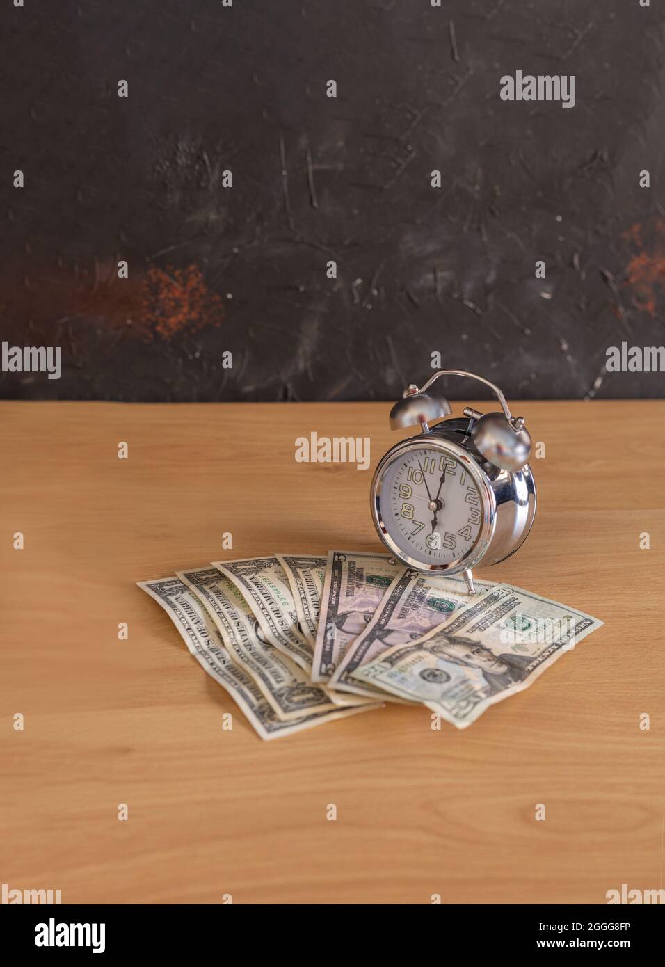 money of different types of dollars on the table and an analog clock ...