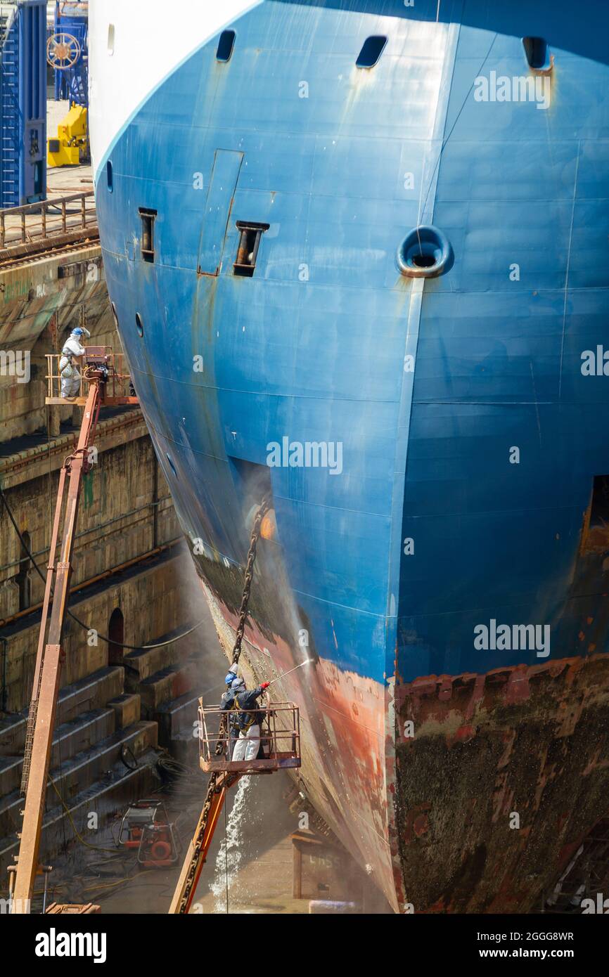 Workers cleaning impurities and removing paint with a pressure ...