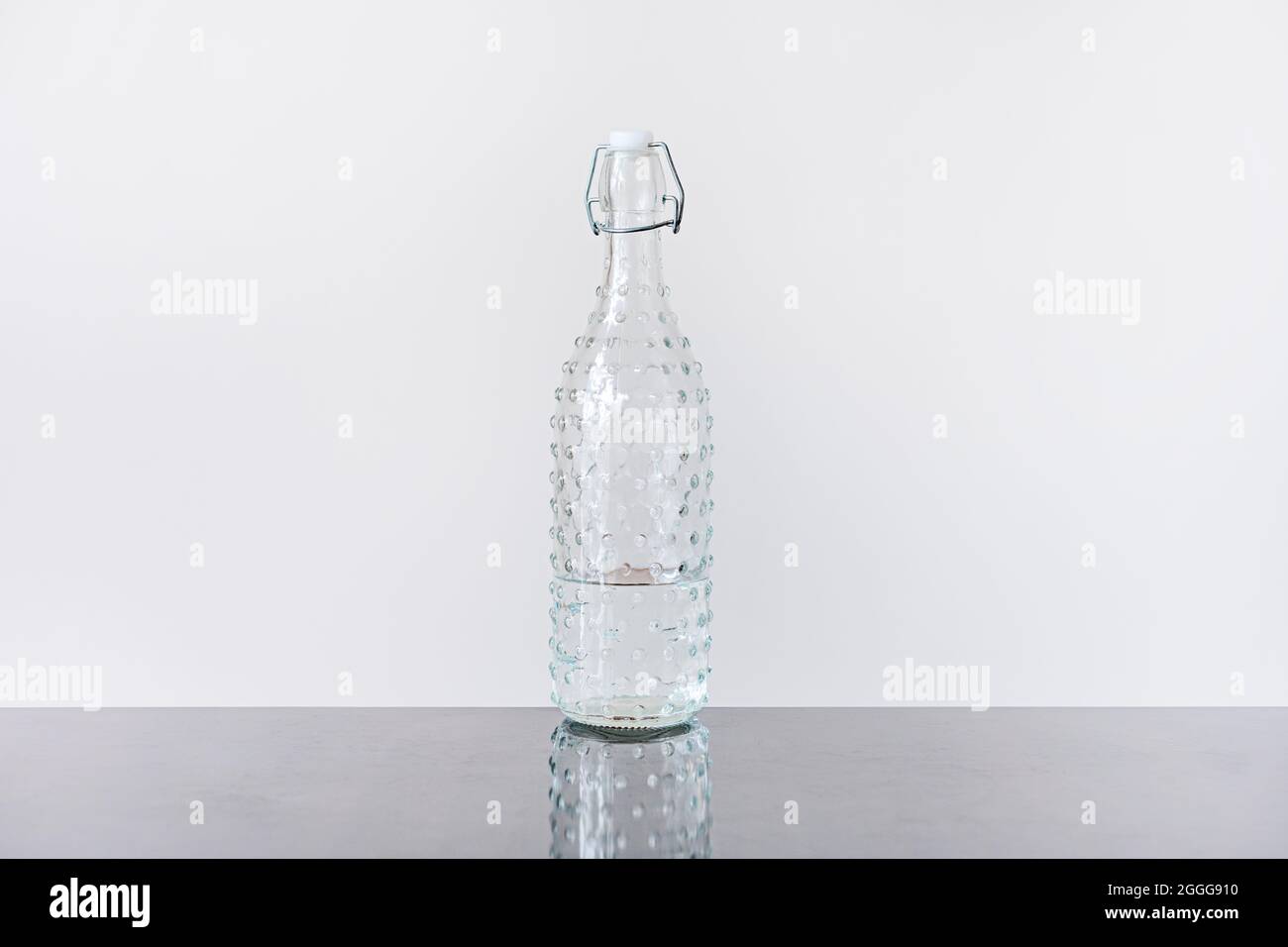 Half full water bottle with white cap on a metal table and white ...