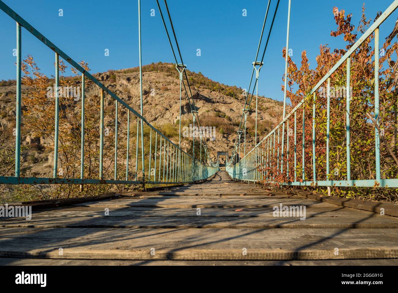 Pedestrian suspension bridge made of wood and metal painted blue with ...
