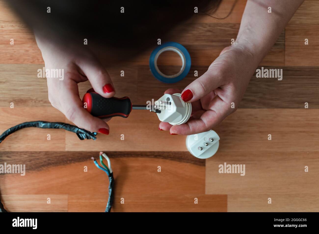 Overhead shot of a woman's hands repairing a plug using a screwdriver ...