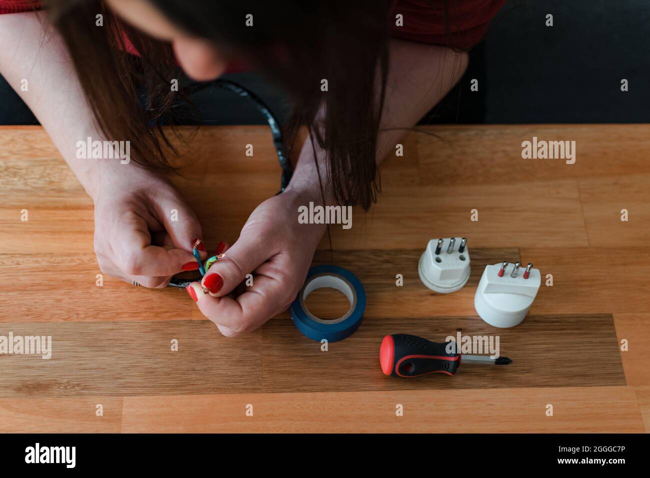 Overhead shot of a woman's hands repairing a plug using a screwdriver ...