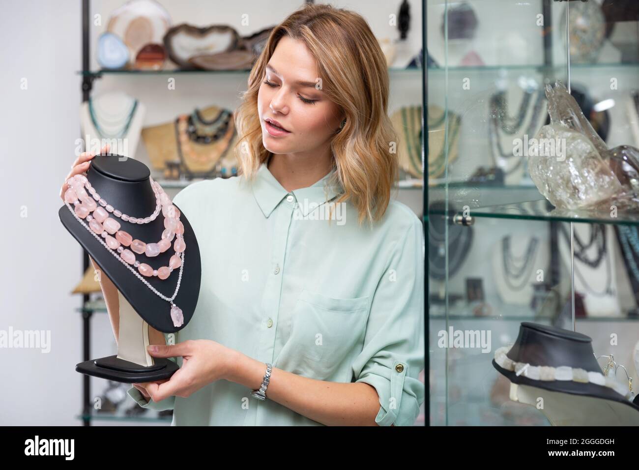 Shop assistant showing necklaces from rose quartz Stock Photo - Alamy