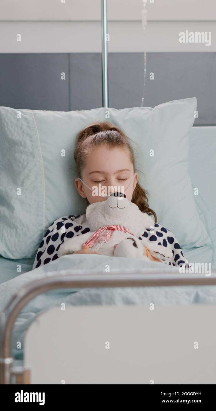 Portrait of hospitalized sick child falling asleep while holding teddy ...