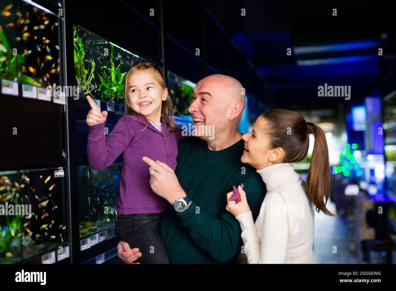 Cheerful parents with little girl looking for aquarium fish Stock Photo ...