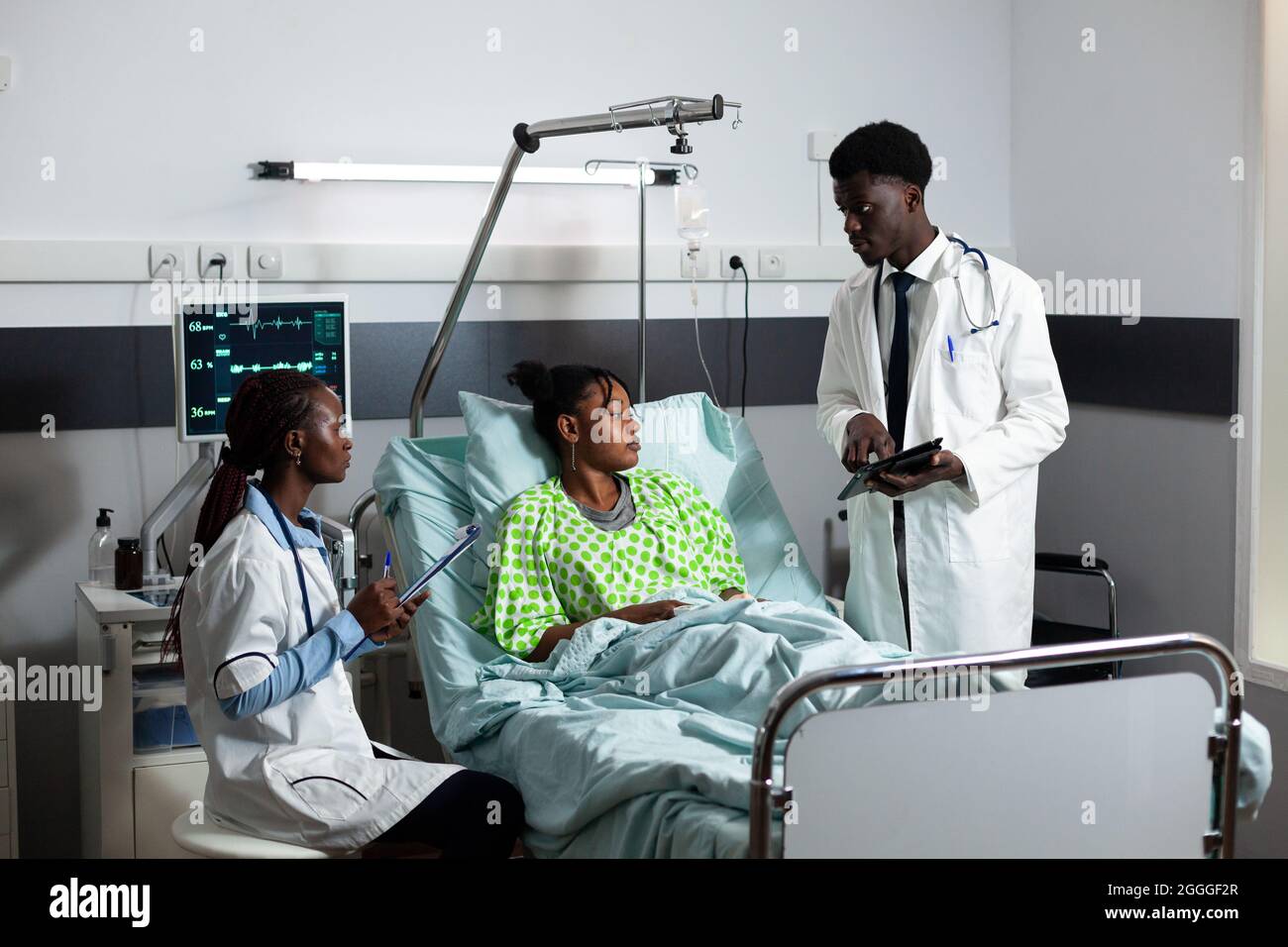 Afro doctors consulting young adult in hospital ward at healthcare ...