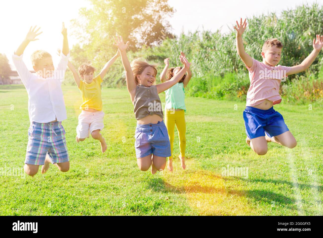Group of children jumping together on green grass Stock Photo - Alamy