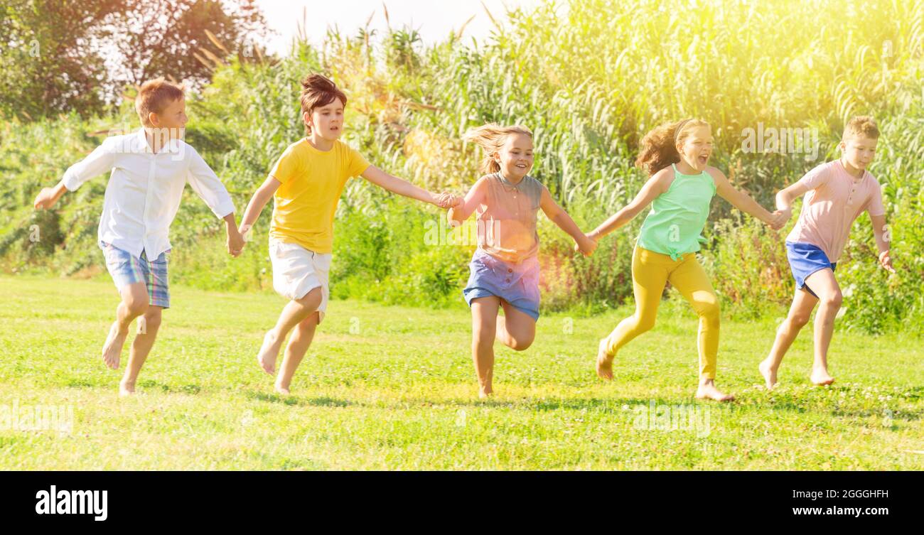 Happy active children running together on grass in park Stock Photo - Alamy