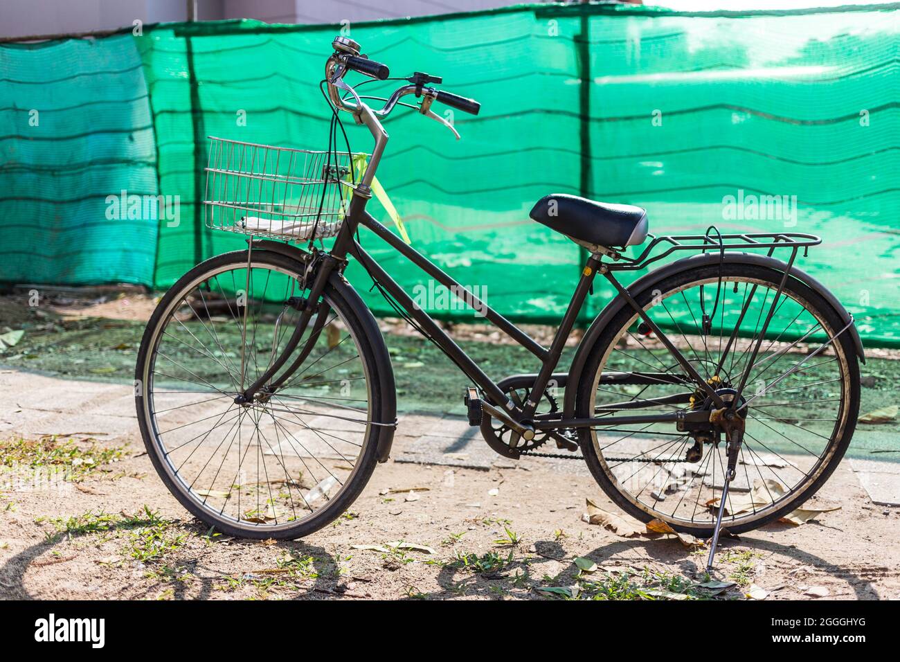 Black vintage bicycle on the sand with green background Stock Photo - Alamy