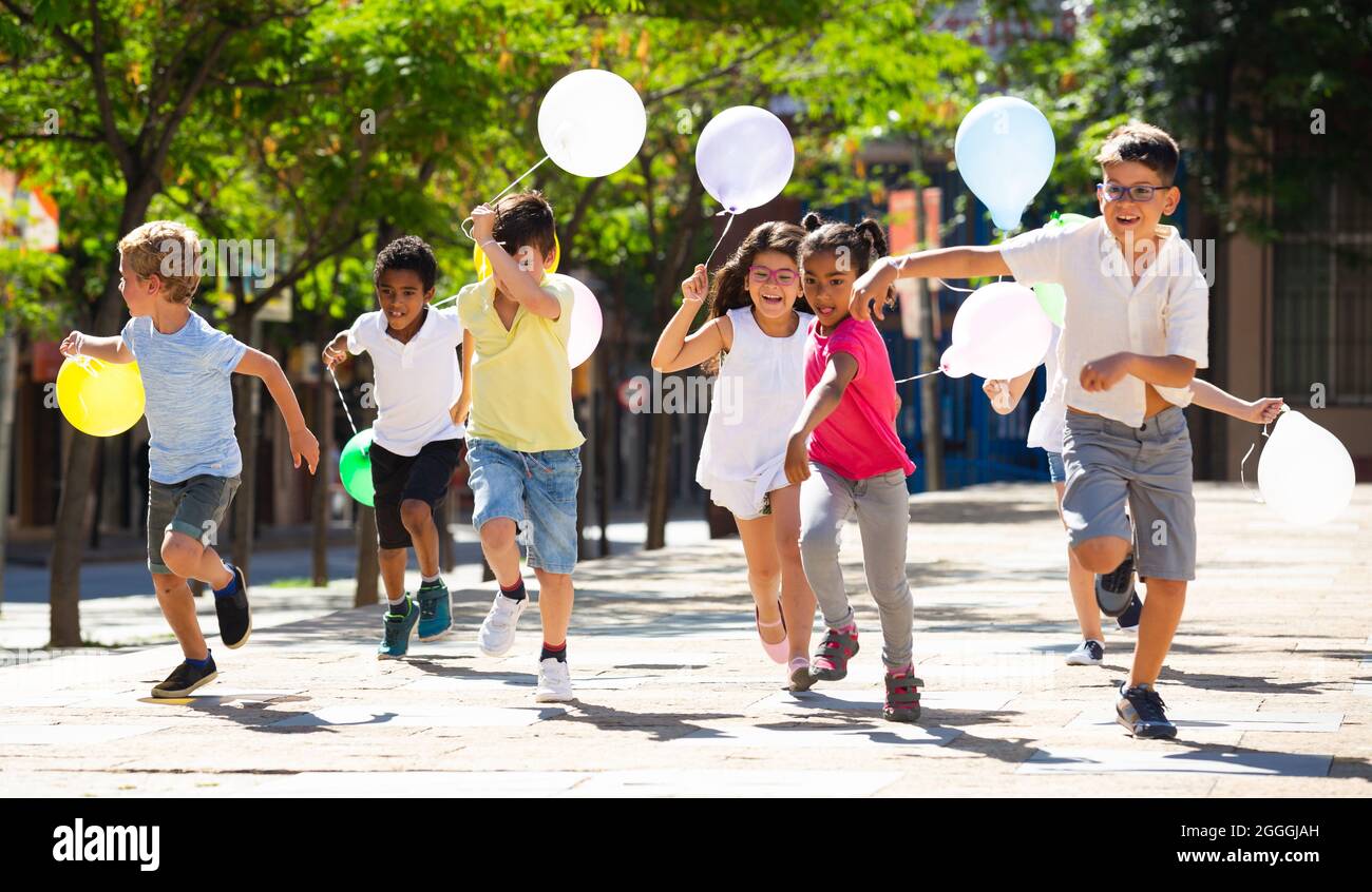 Happy children with balloons run on the summer city street Stock Photo ...