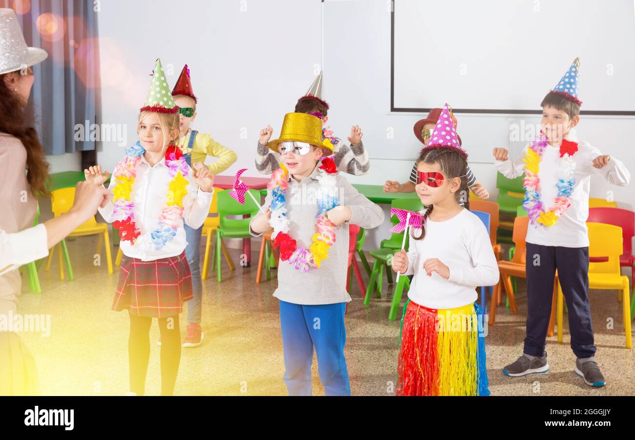 Kids and teacher in funny hats dancing Stock Photo - Alamy
