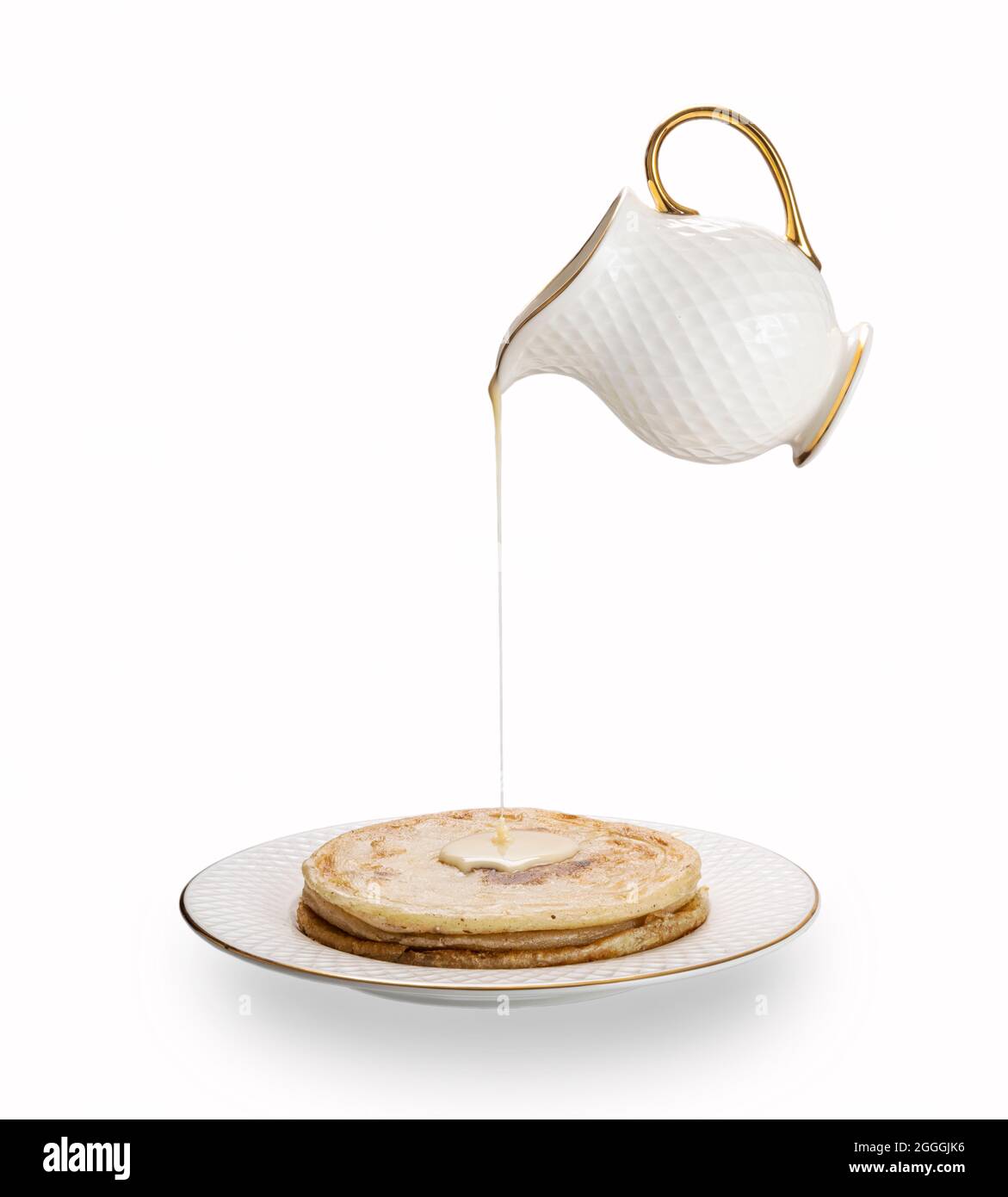 Levitating jug pouring sweetened condensed milk on pieces of freshly ...