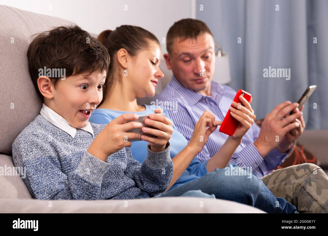 Modern family sitting with smartphones in home interior Stock Photo - Alamy