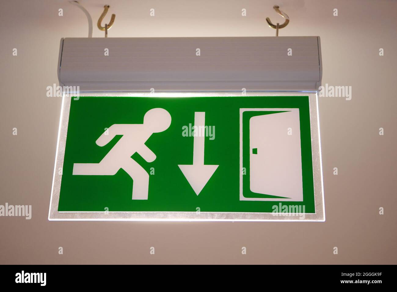 Green evacuation direction sign on ceiling. Emergency exit sign with ...