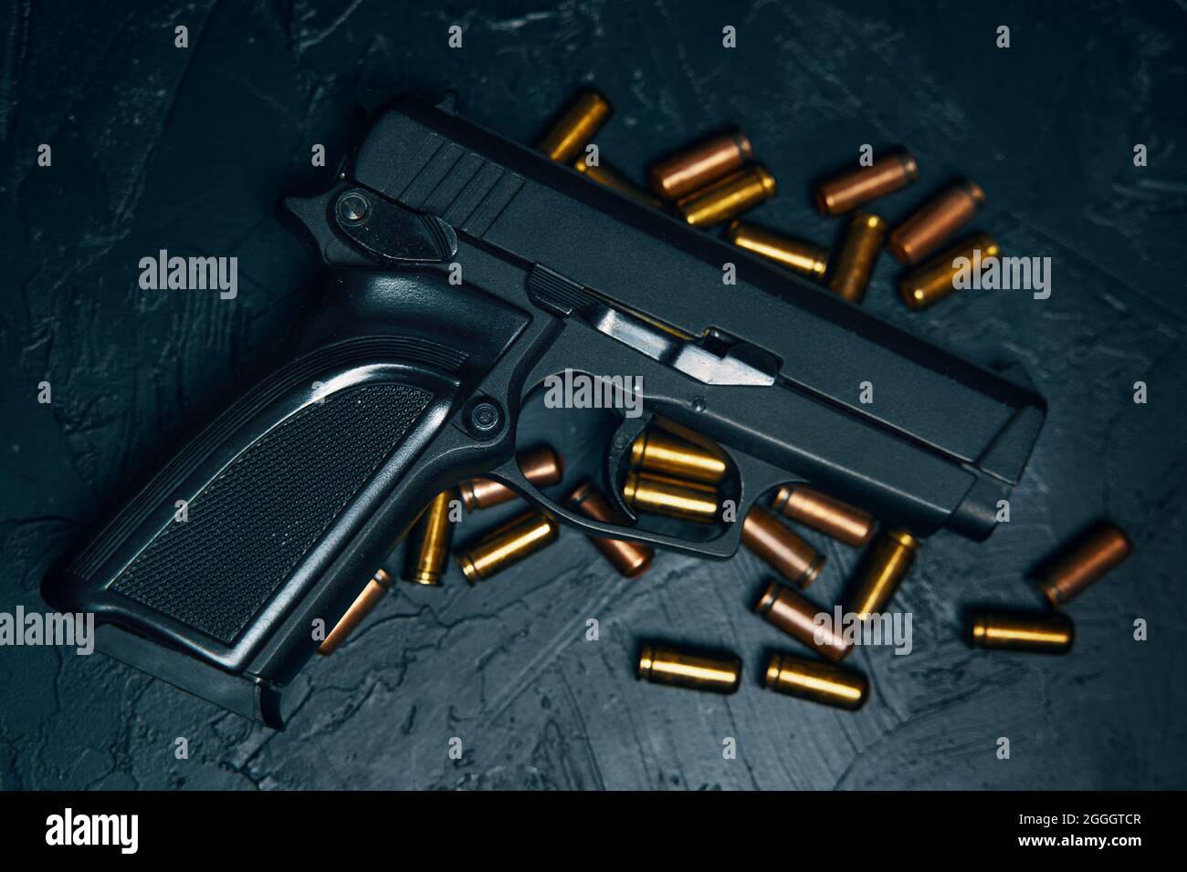 Automatic firearms with bullets. Black pistol with cartridges on table ...