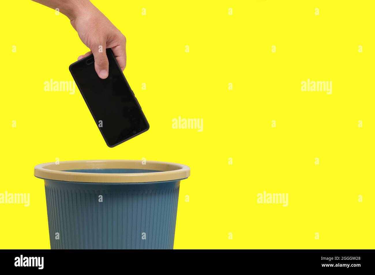 Man hand throws cell phone into trash can on yellow background Stock ...