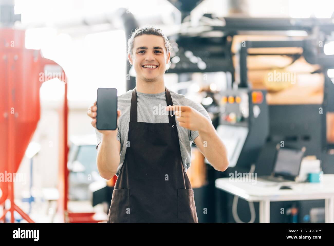 Professional barista holding phone screen near roasting coffee beans in ...