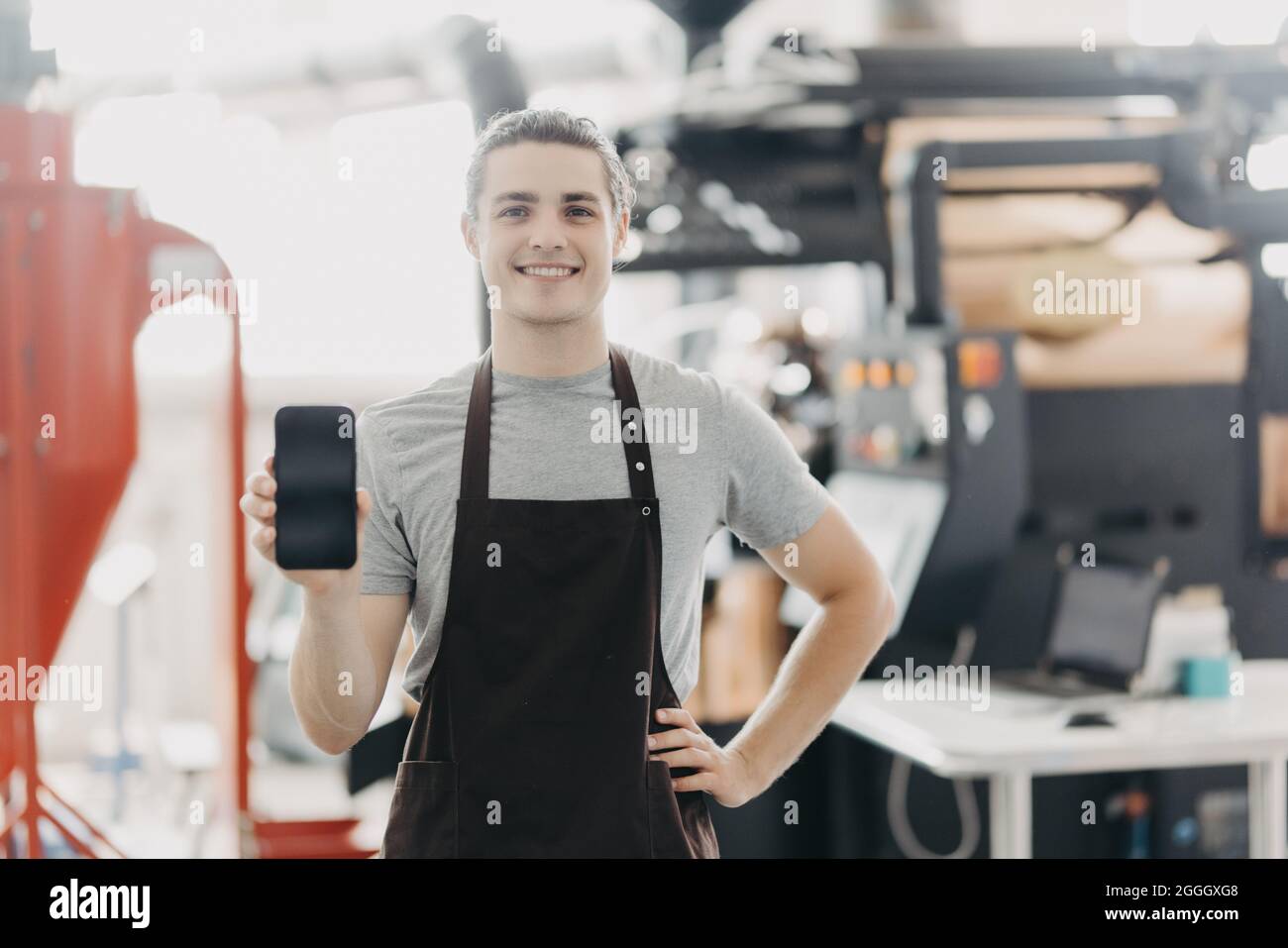 Professional barista holding phone screen near roasting coffee beans in ...