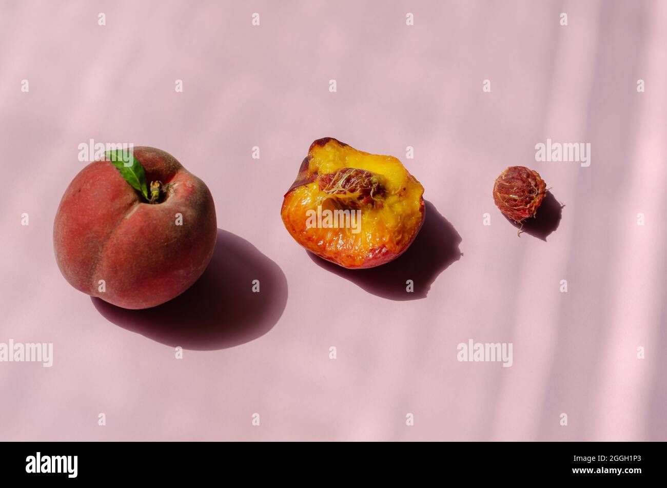 Minimalist composition with peaches on a pink background. Ripe, bitten ...