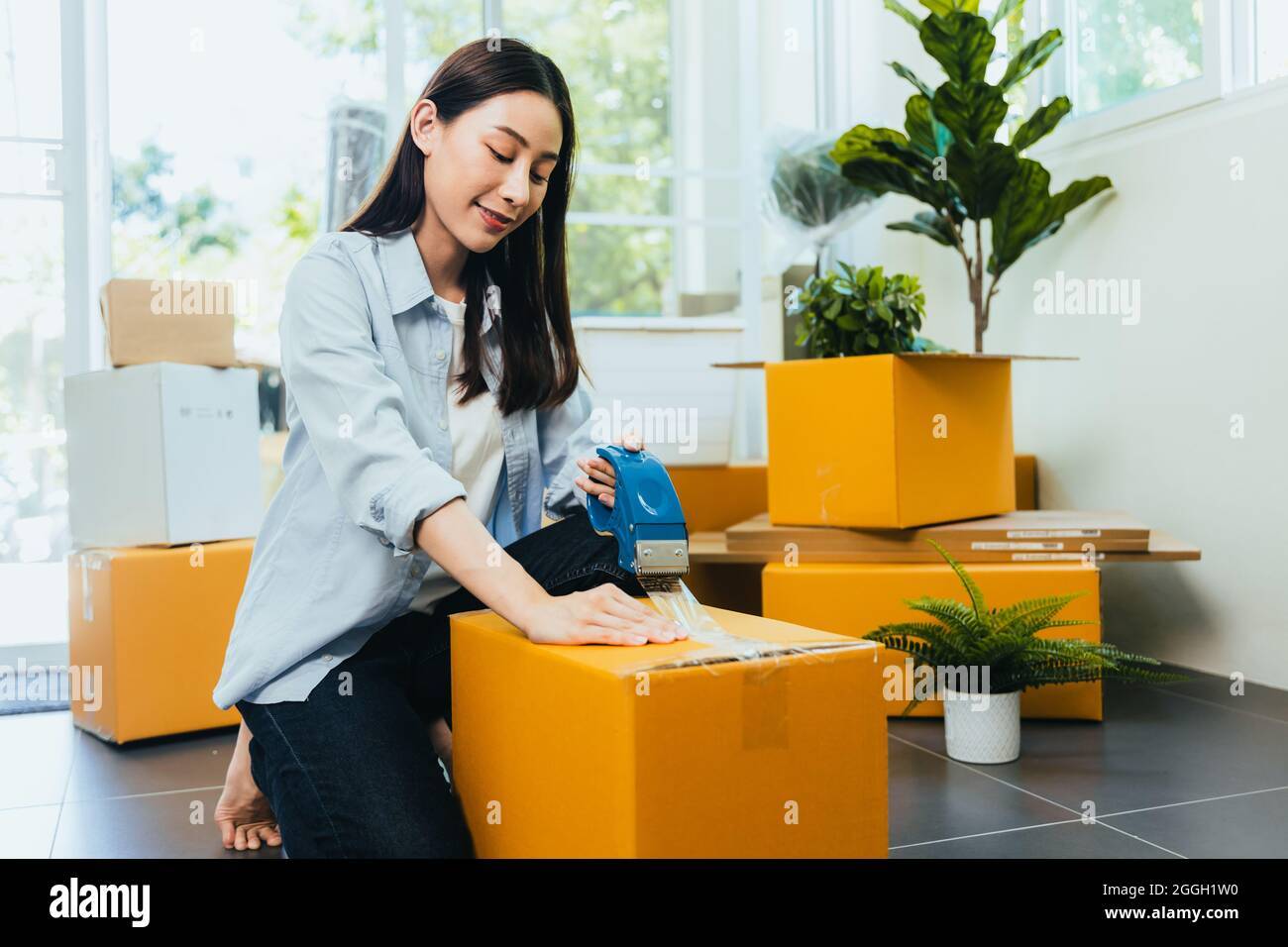 Asian woman packing box to move new home Stock Photo - Alamy