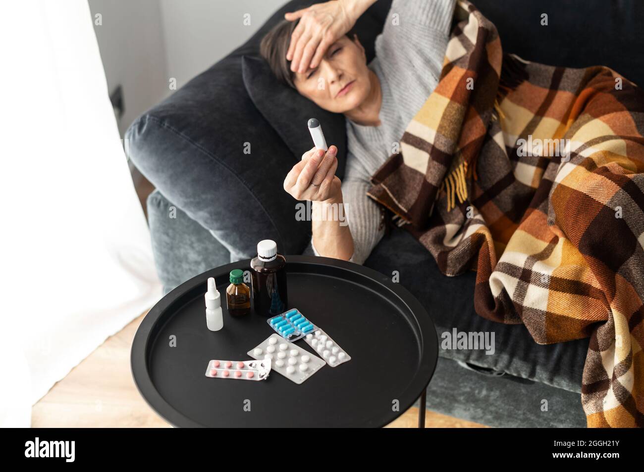 Senior woman feel sick, a mature older lady lying covered blanket ...