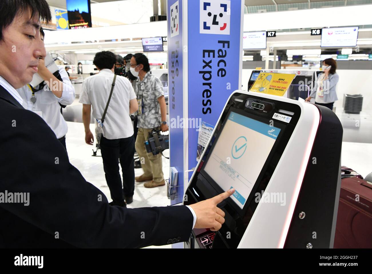 A staff demonstrates JAL's check-in procedures using Face Express at ...