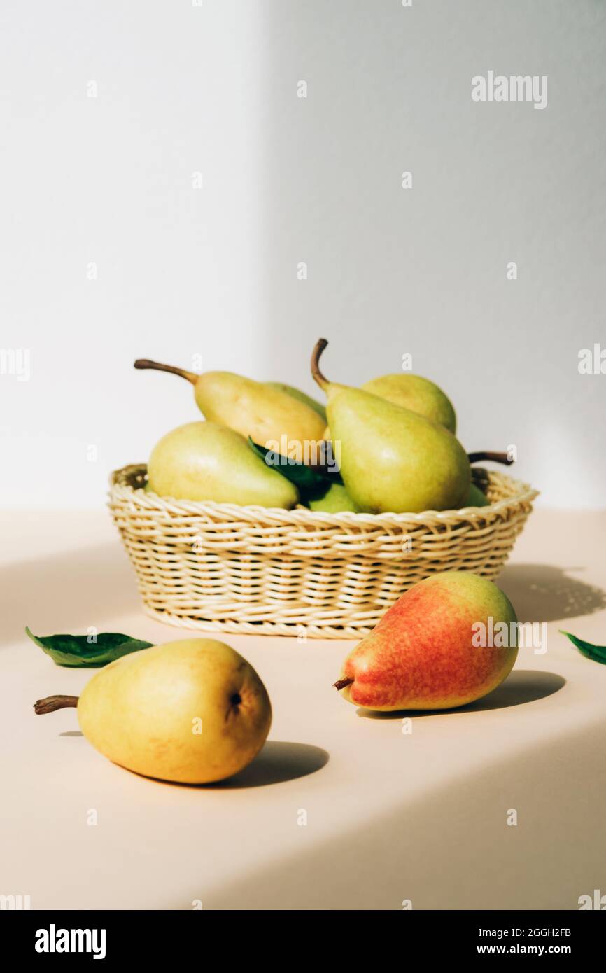 Fresh ripe pears in the basket on beige table. Healthy vegan food ...