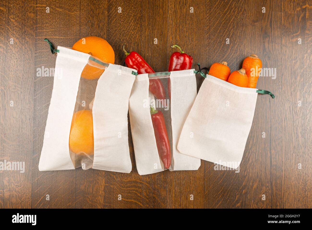 Three handmade reusable sacks with some vegetables in them laying on a ...