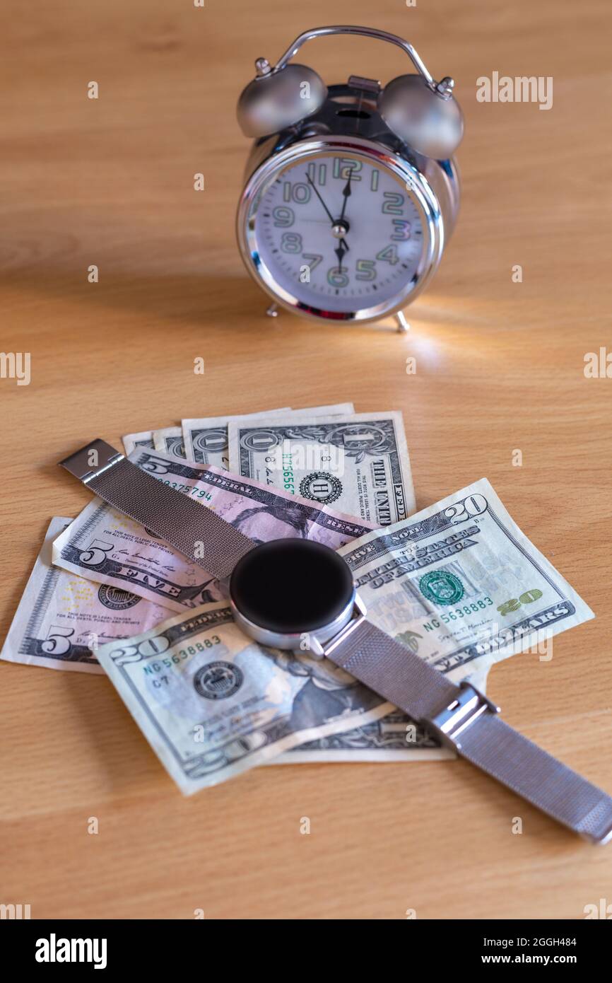 dollar money placed on a table with an analog clock and a digital clock ...