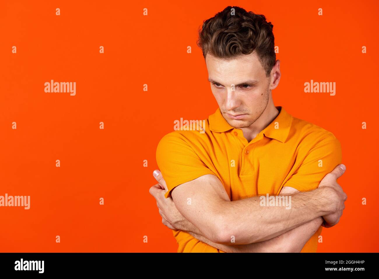 Young man standing with crossed hands isolated on orange color studio ...