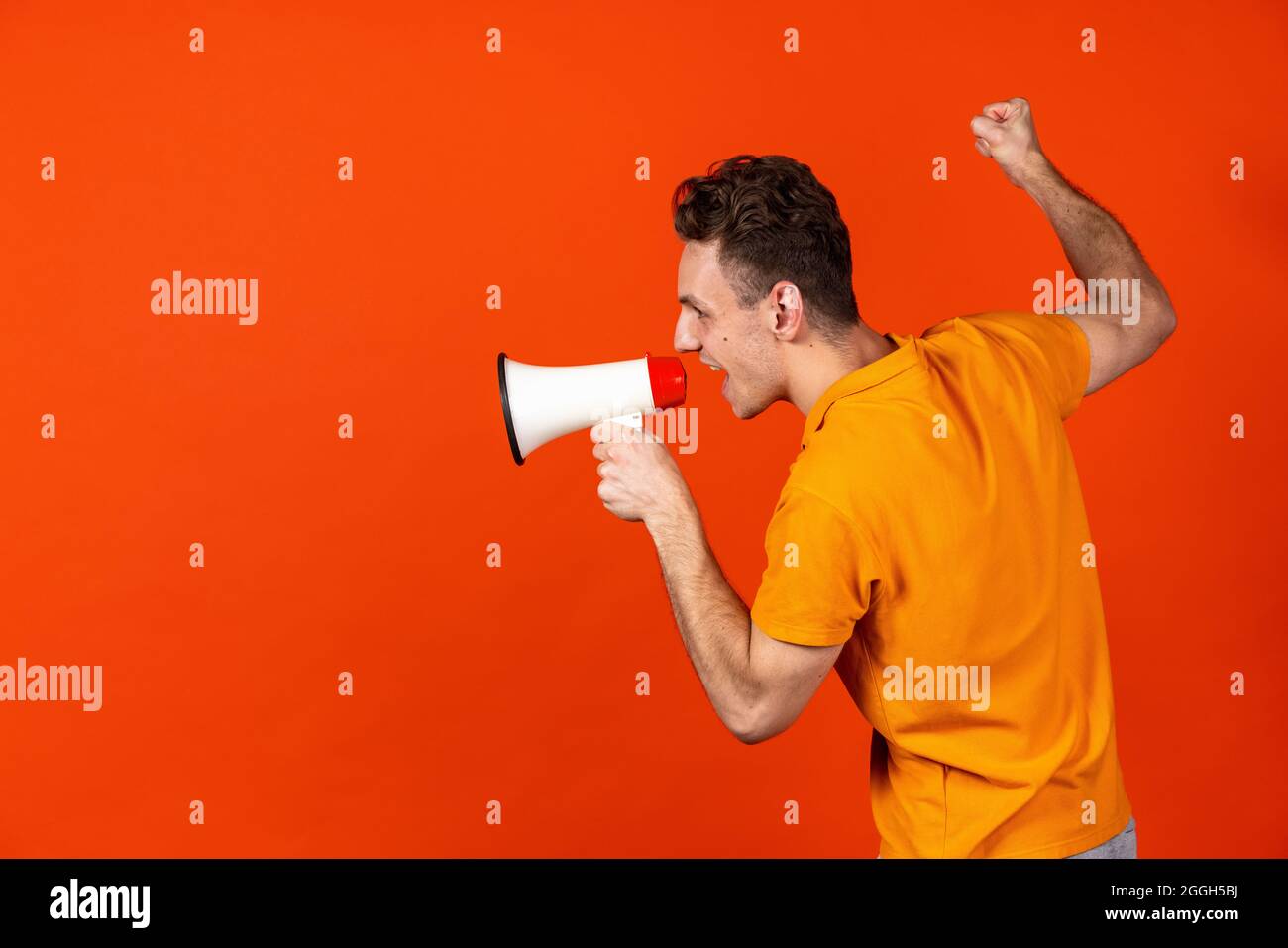 Portrait of young Caucasian man shouting at megaphone isolated on ...