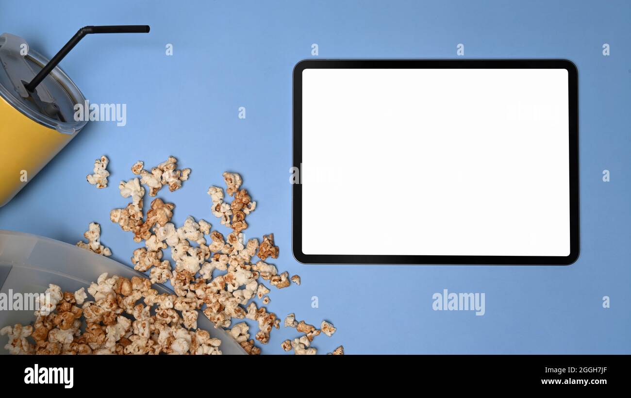 Digital tablet, popcorn bucket and glass of refresh drink on blue ...