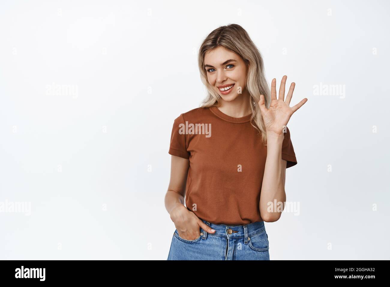 Smiling pretty girl waving hand and say hello, greeting you with ...