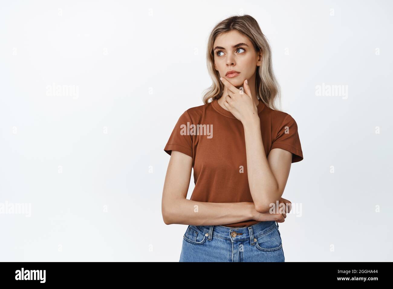 Image of thoughtful blond girl pondering, looking aside while thinking ...
