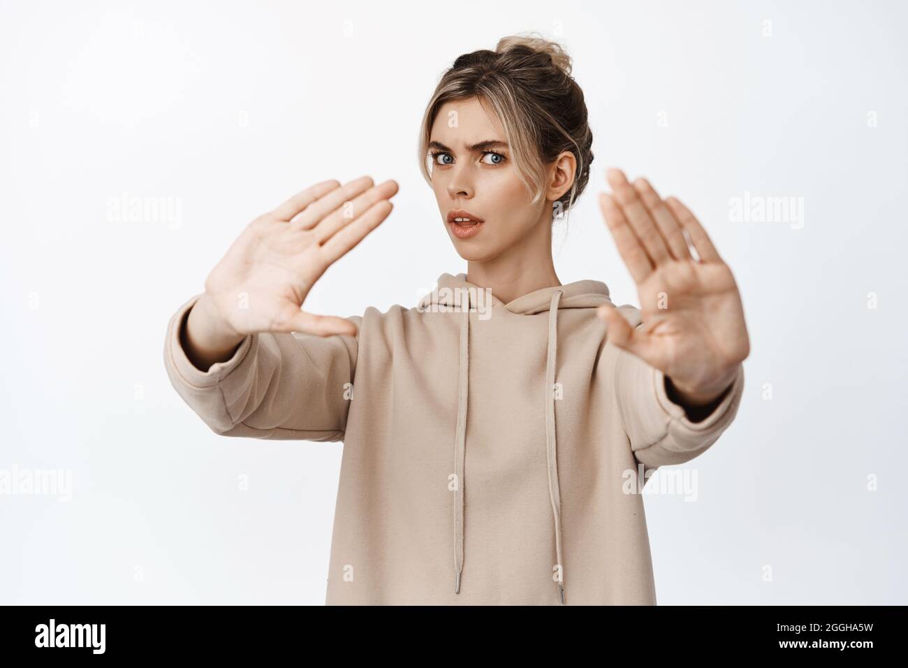 Reluctant young woman asking to stop, extending hands to block, decline ...