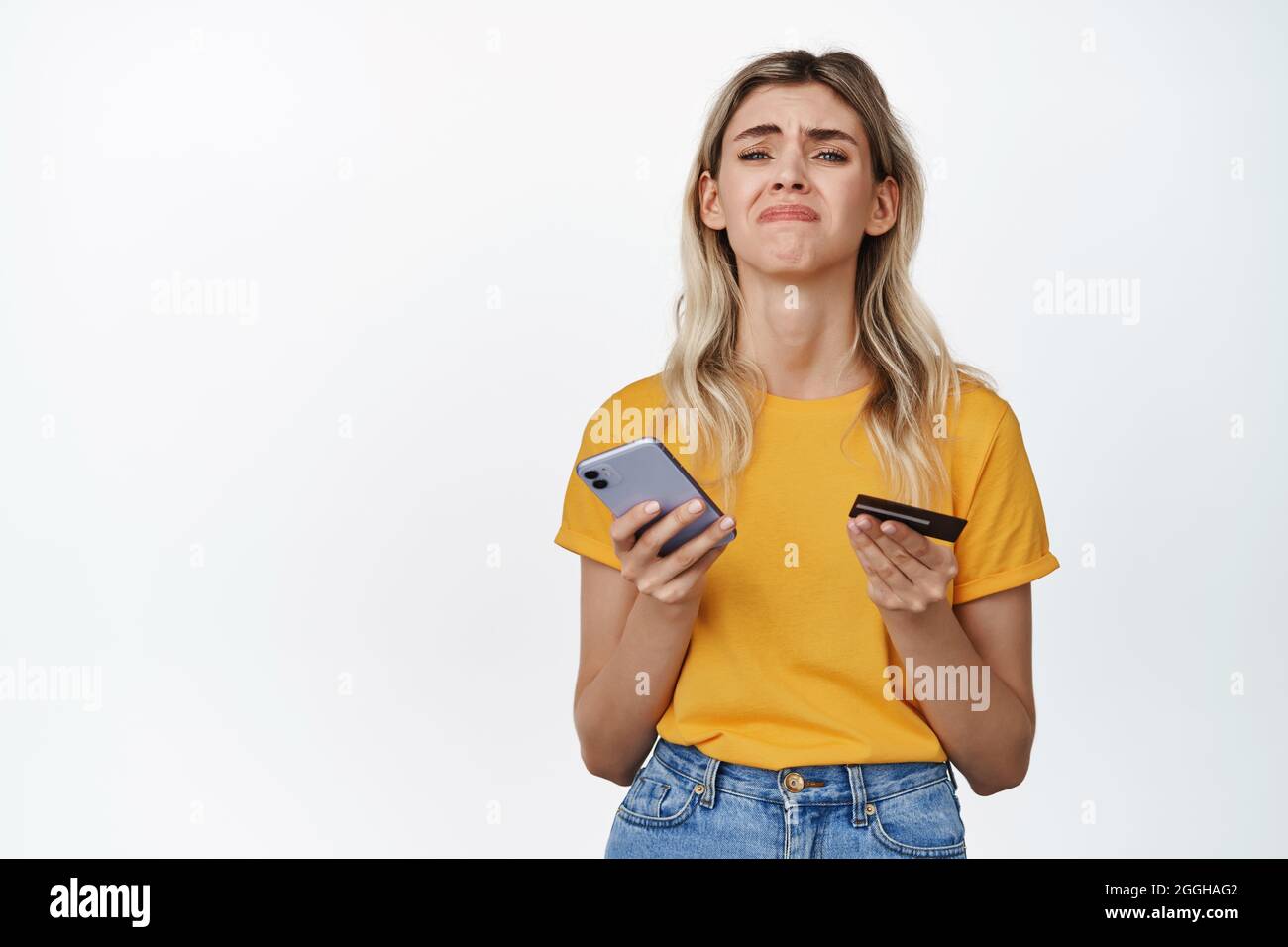 Upset girl holding smartphone and credit card, concept of woman lacking ...