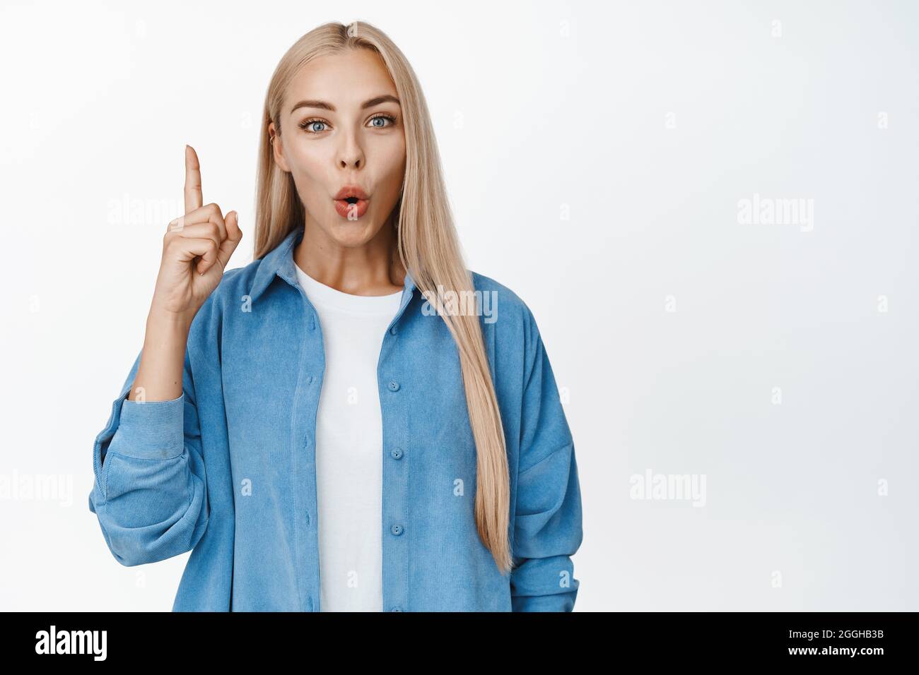 Intrigued girl pointing finger up, say wow, looking impressed, standing ...