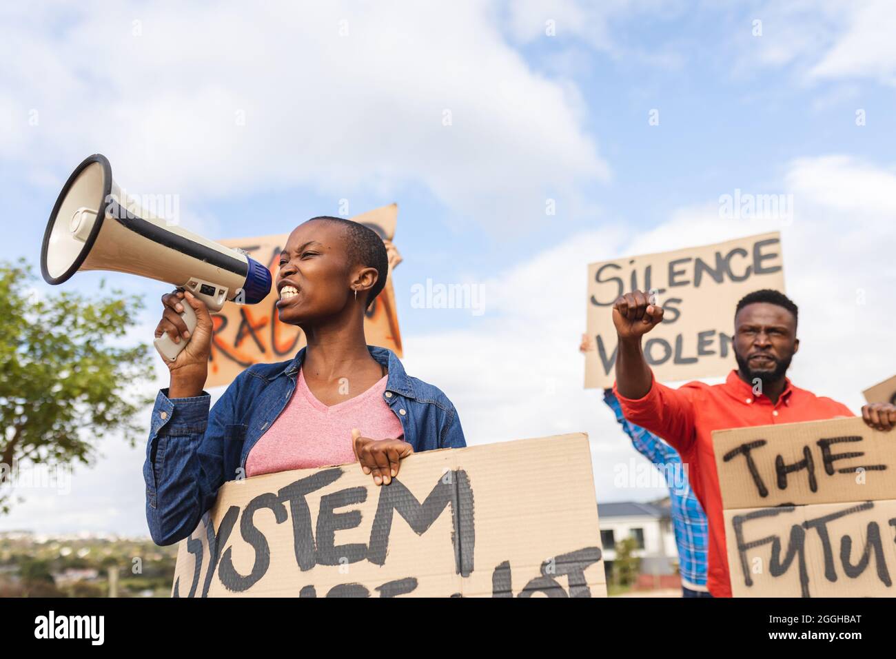 African american woman using megaphone and holding placard at a protest ...