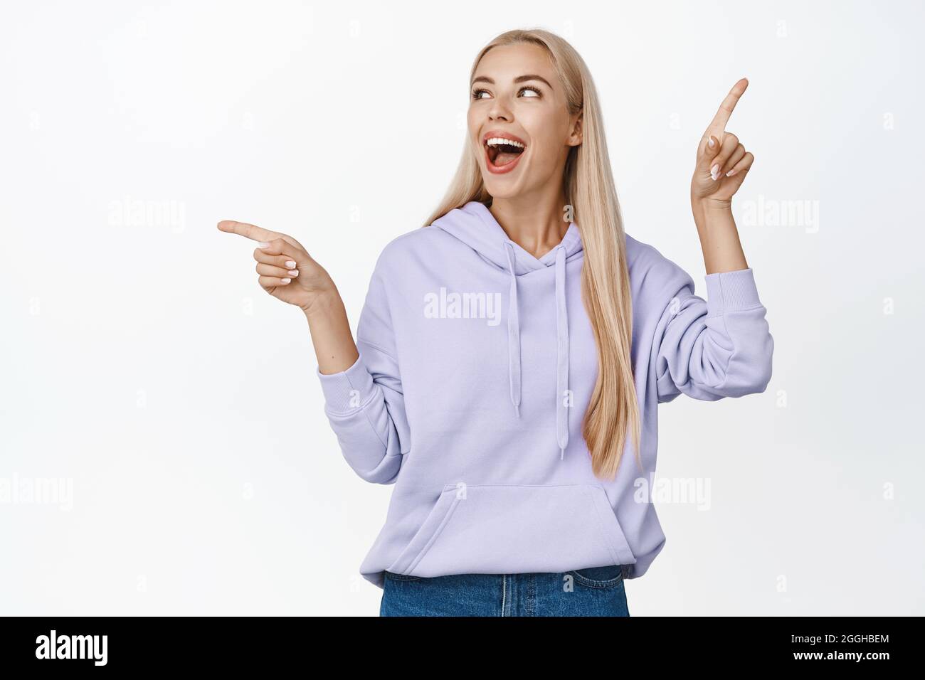 Fascinated girl pointing fingers sideways and turn head aside, showing ...