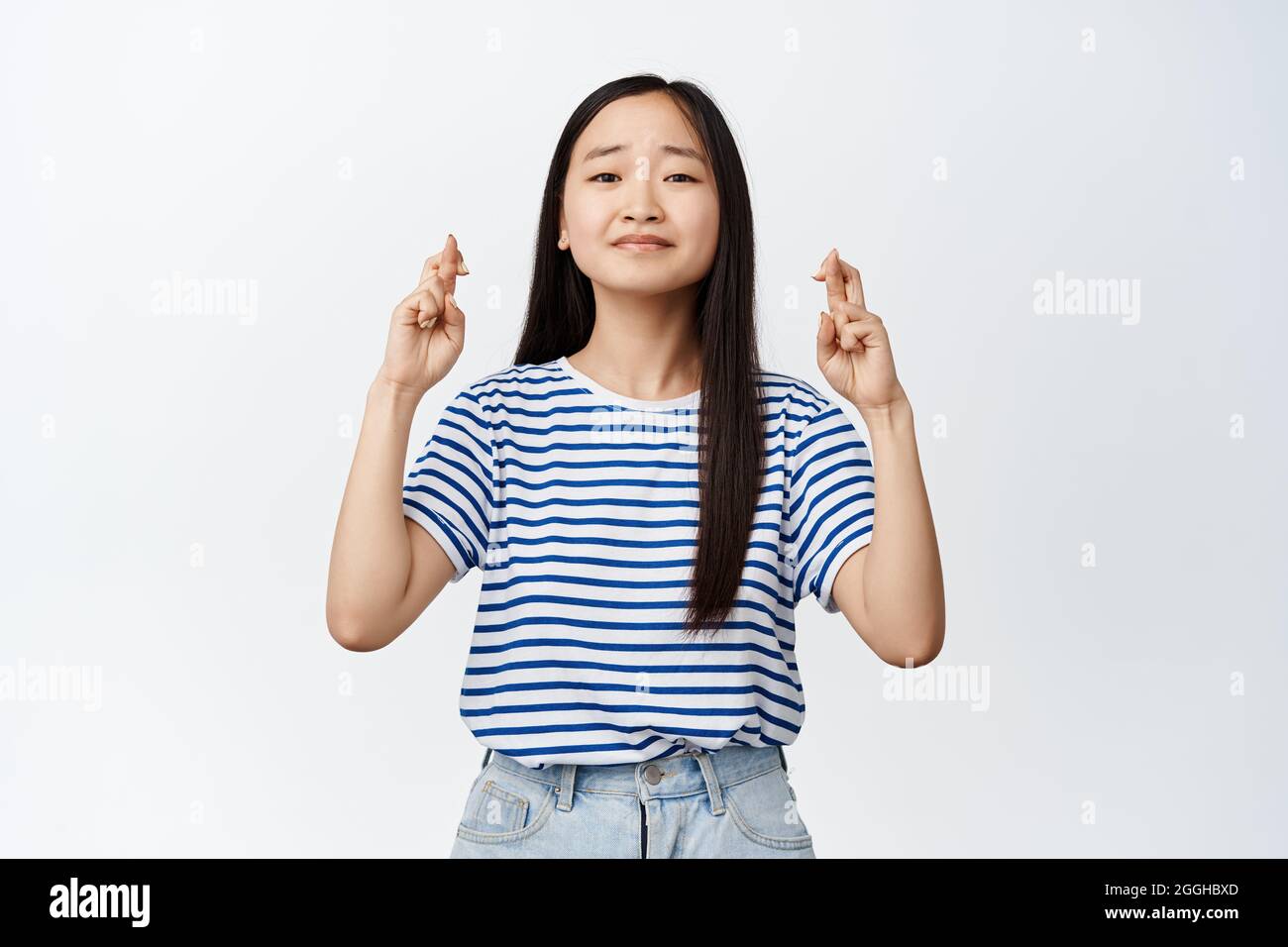 Nervous asian girl looking hopeful at camera, praying with fingers ...