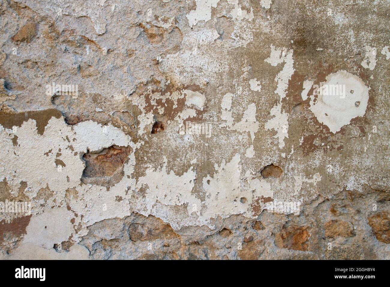 Old traditional limewashed stone wall with peeling plaster, white ...