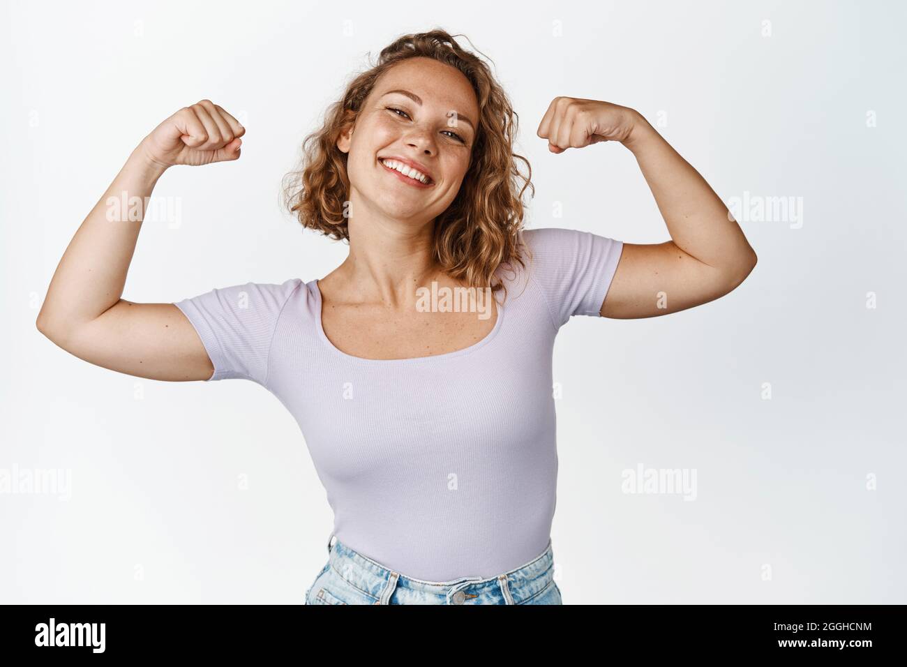 Women power. Smiling pretty girl flexing biceps, showing her strength ...