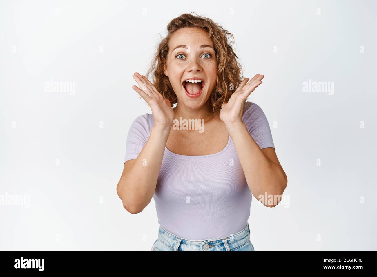 Excited blond girl laughing, receive big surprise news and show amazed ...