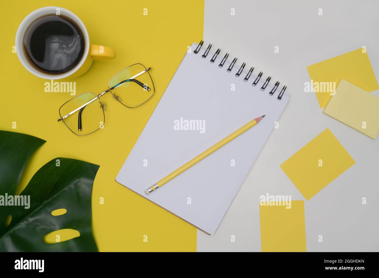 Notebook, coffee cup, sticky notes and glasses on yellow background ...
