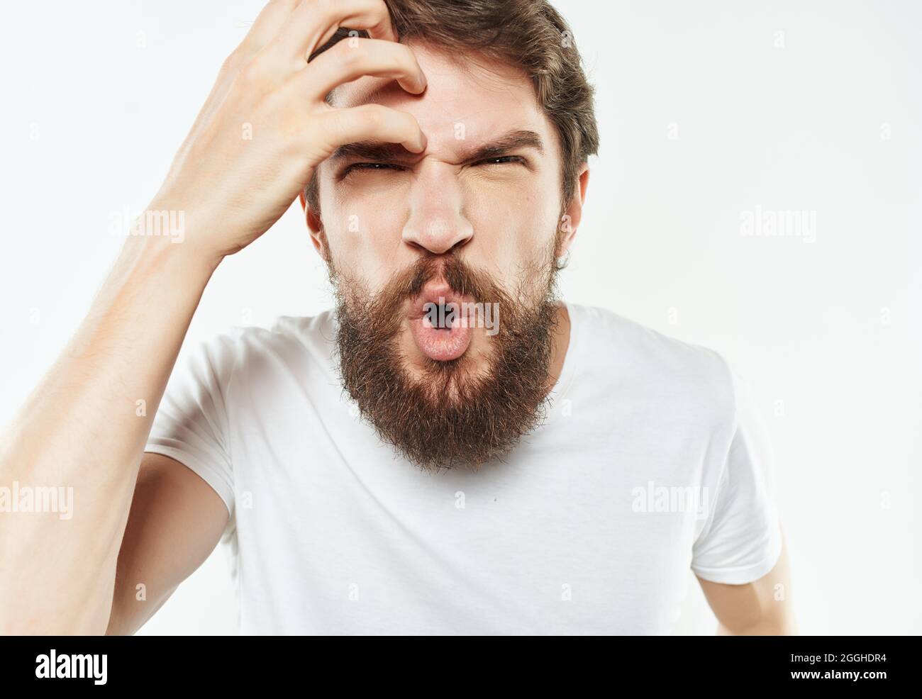 Man in a white t-shirt irritated facial expression light background ...