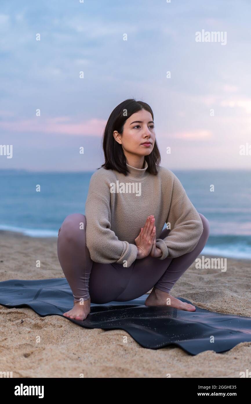 Young woman practicing yoga at the beach at sunrise. Healthy lifestyle ...