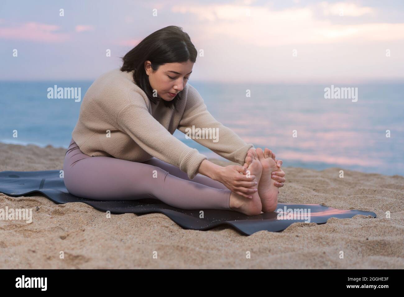 Young woman practicing yoga at the beach at sunrise. Healthy lifestyle ...