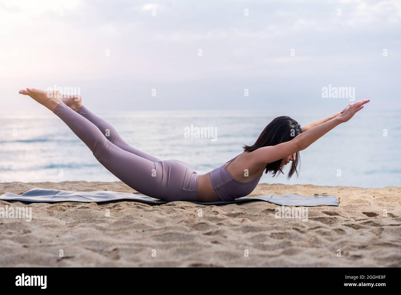 Young woman practicing yoga at the beach at sunrise. Healthy lifestyle ...