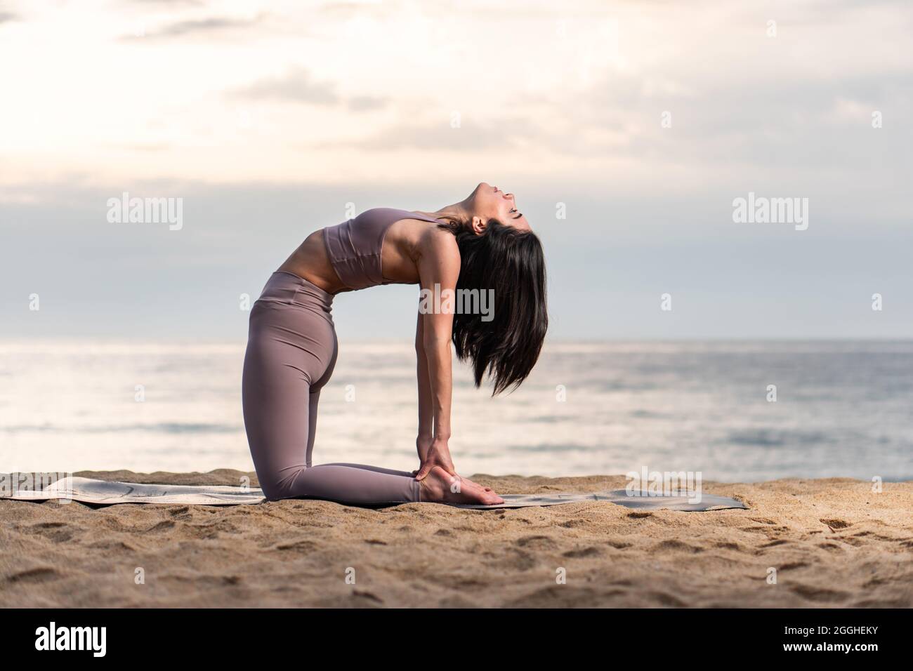 Young woman practicing yoga at the beach at sunrise. Healthy lifestyle ...